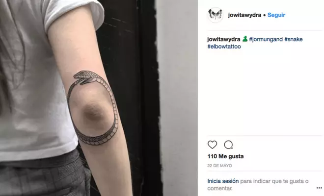 En fin tatuering av en orm på armbågarna